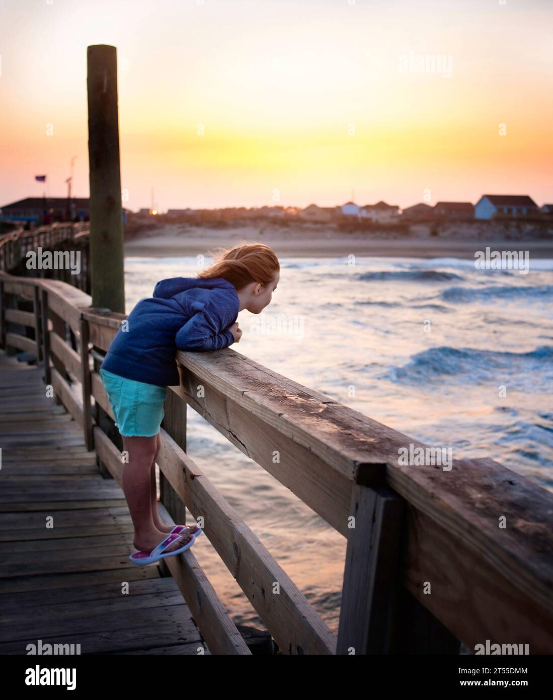 Little girl looking at ocean on pier during sunset Stock Photo - Alamy