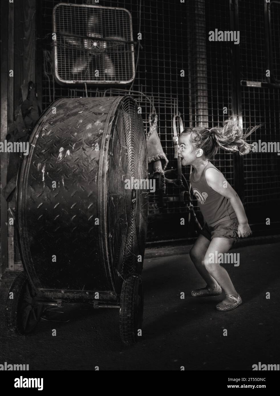 Cute little girl yelling into huge fan with hair blowing Stock Photo ...