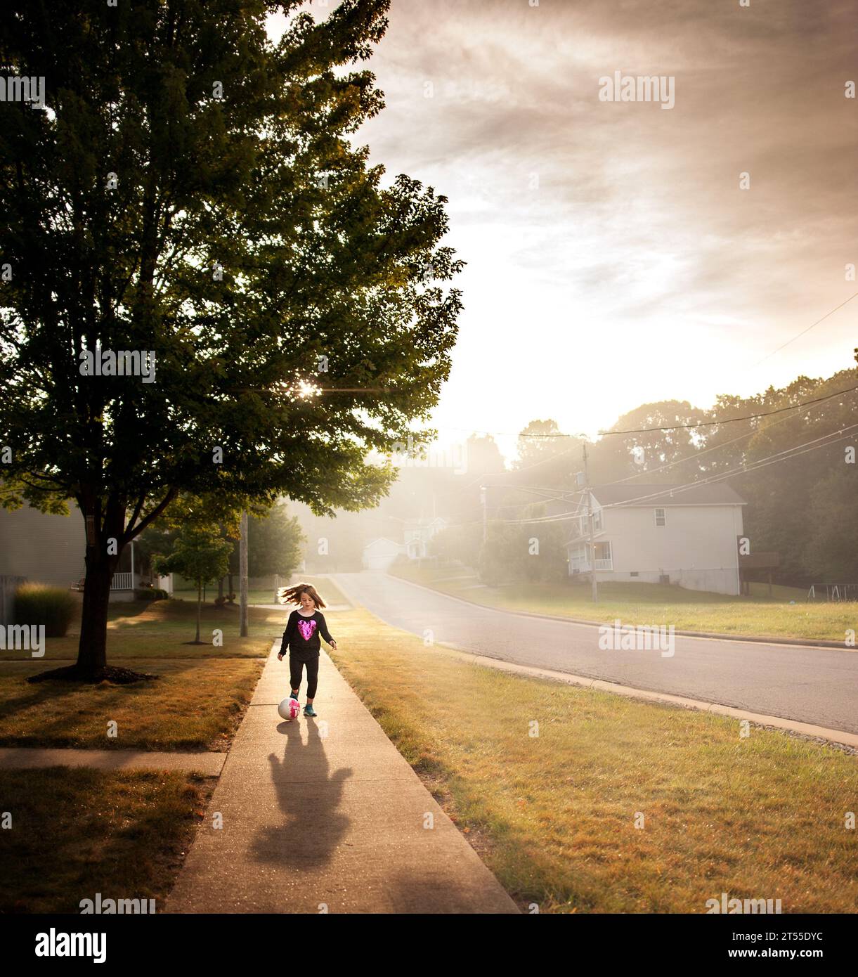 Little girl dribbling soccer ball down sidewalk Stock Photo - Alamy