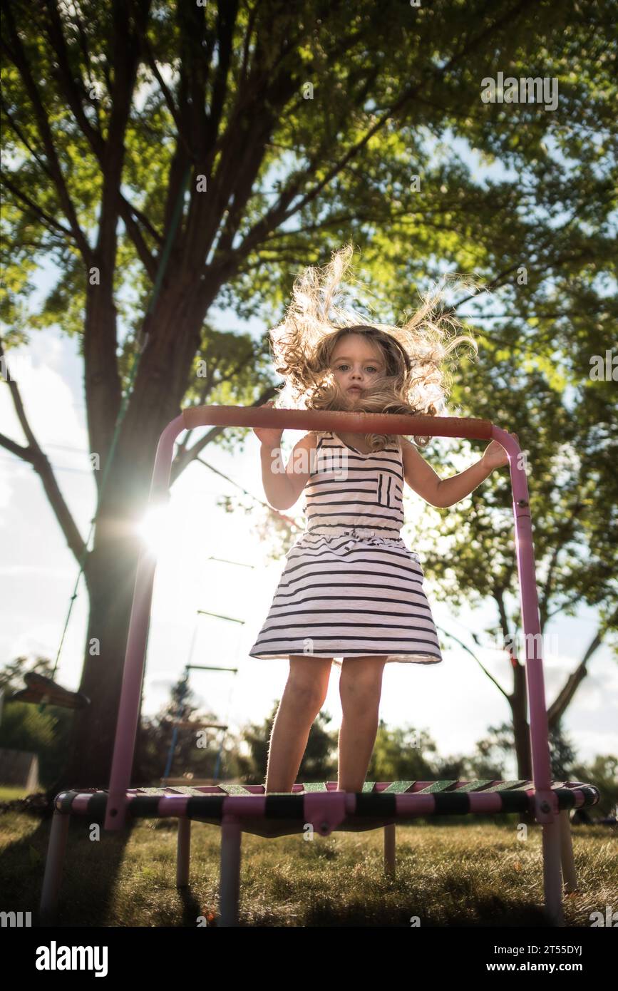 Beautiful little girl jumping on trampoline in back yard Stock Photo ...