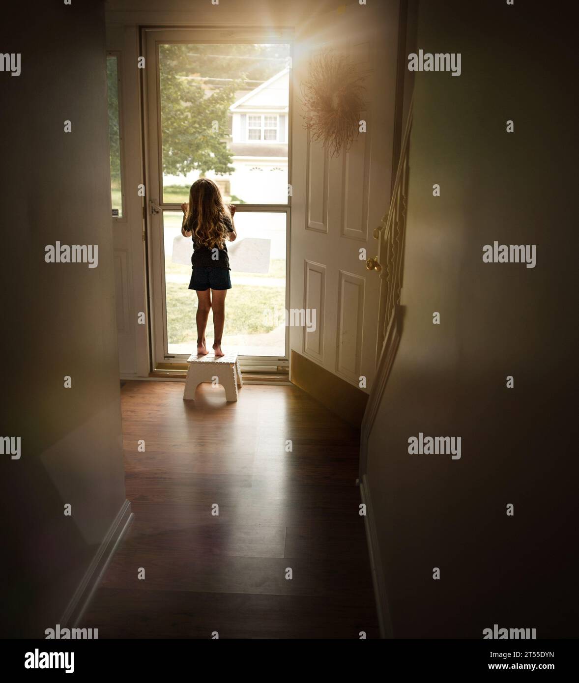 Toddler standing on stool looking out home window Stock Photo - Alamy
