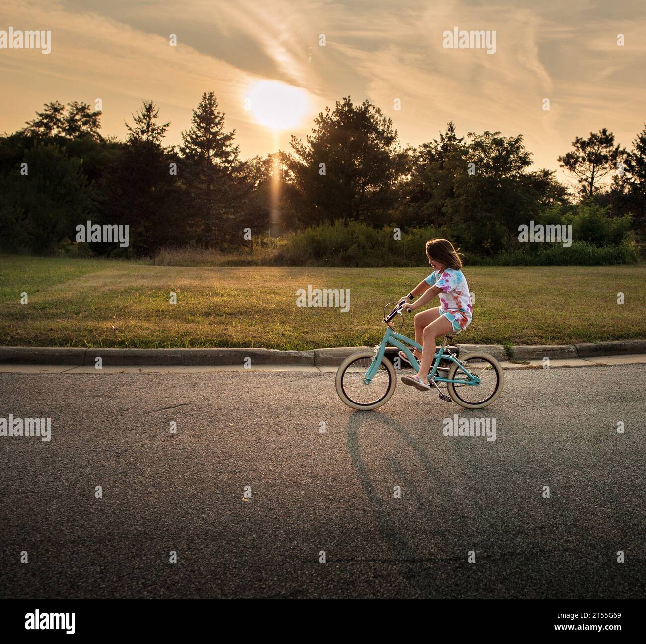 Young girl riding bike outdoors at sunset Stock Photo - Alamy