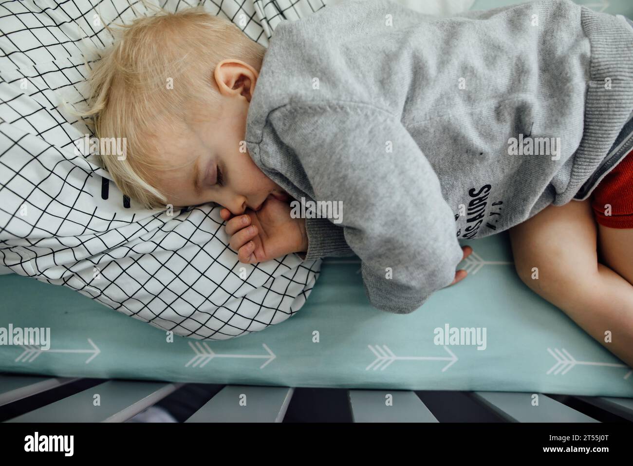Overhead shot of little boy sleeping on side in crib sucking his Stock ...