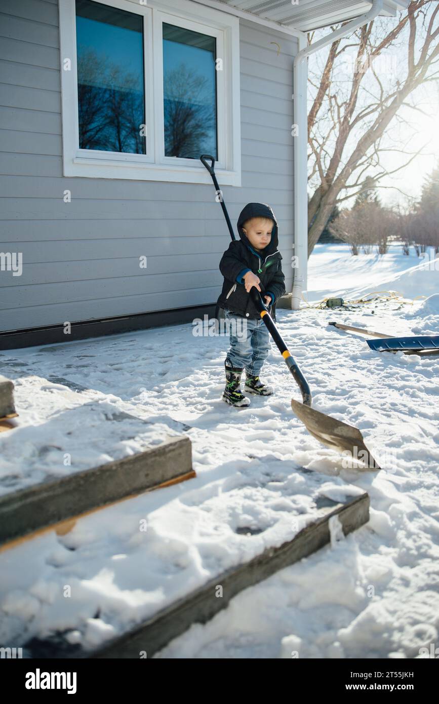 Front view of little boy shoveling steps while standing in fron Stock ...
