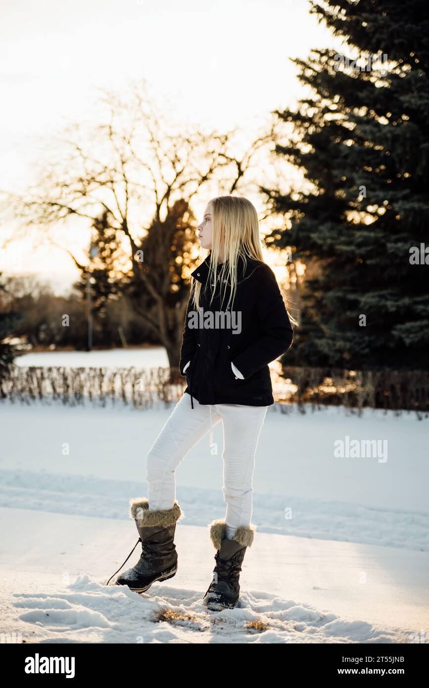 Side view of teen girl with long blond hair standing in snow out Stock ...