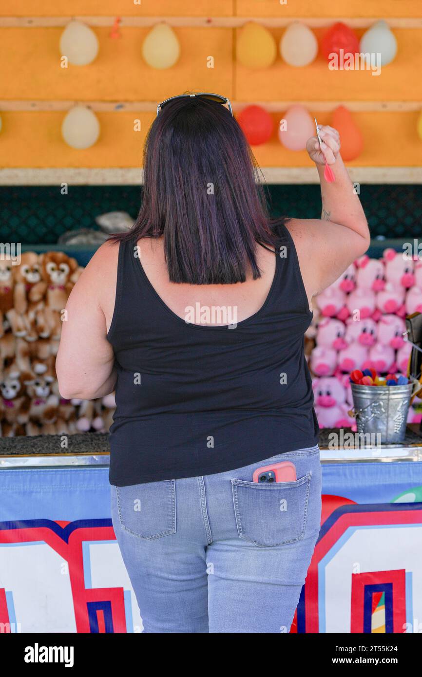 A lady playing darts at the county fair Stock Photo - Alamy