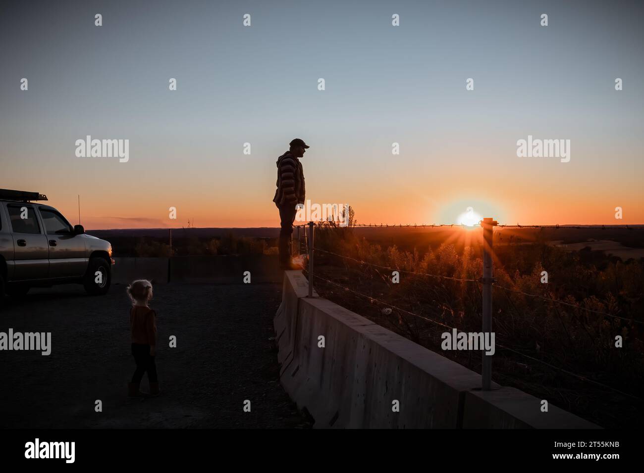 Person standing at scenic overlook watching sunset Stock Photo - Alamy