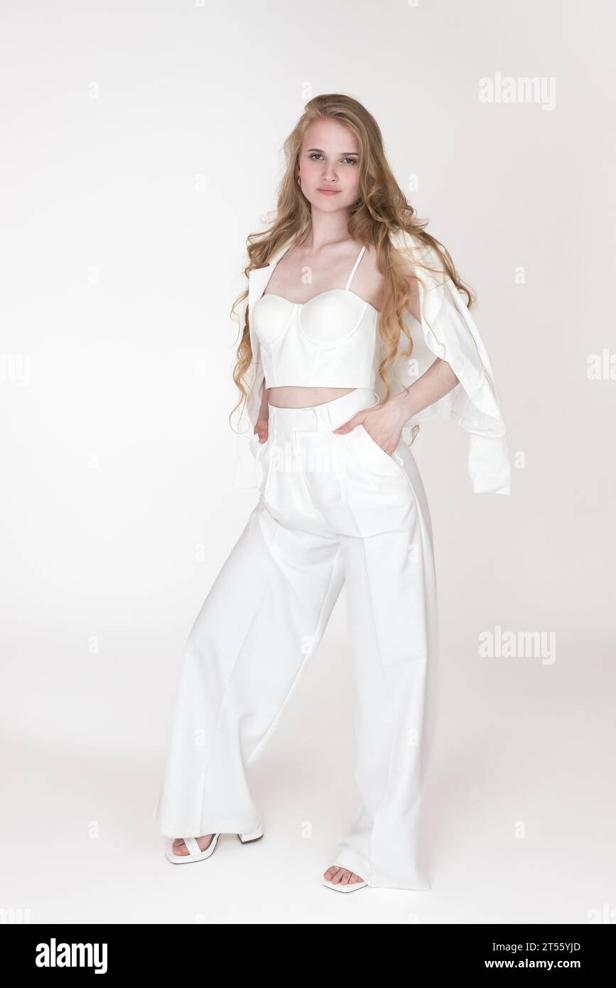 Full length portrait of fashion model holding hands in trousers pockets ...