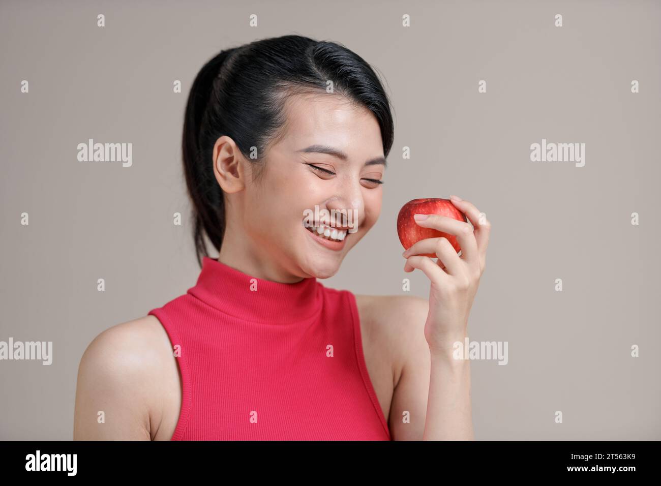 Woman with perfect smile holding apple on beige background Stock Photo ...