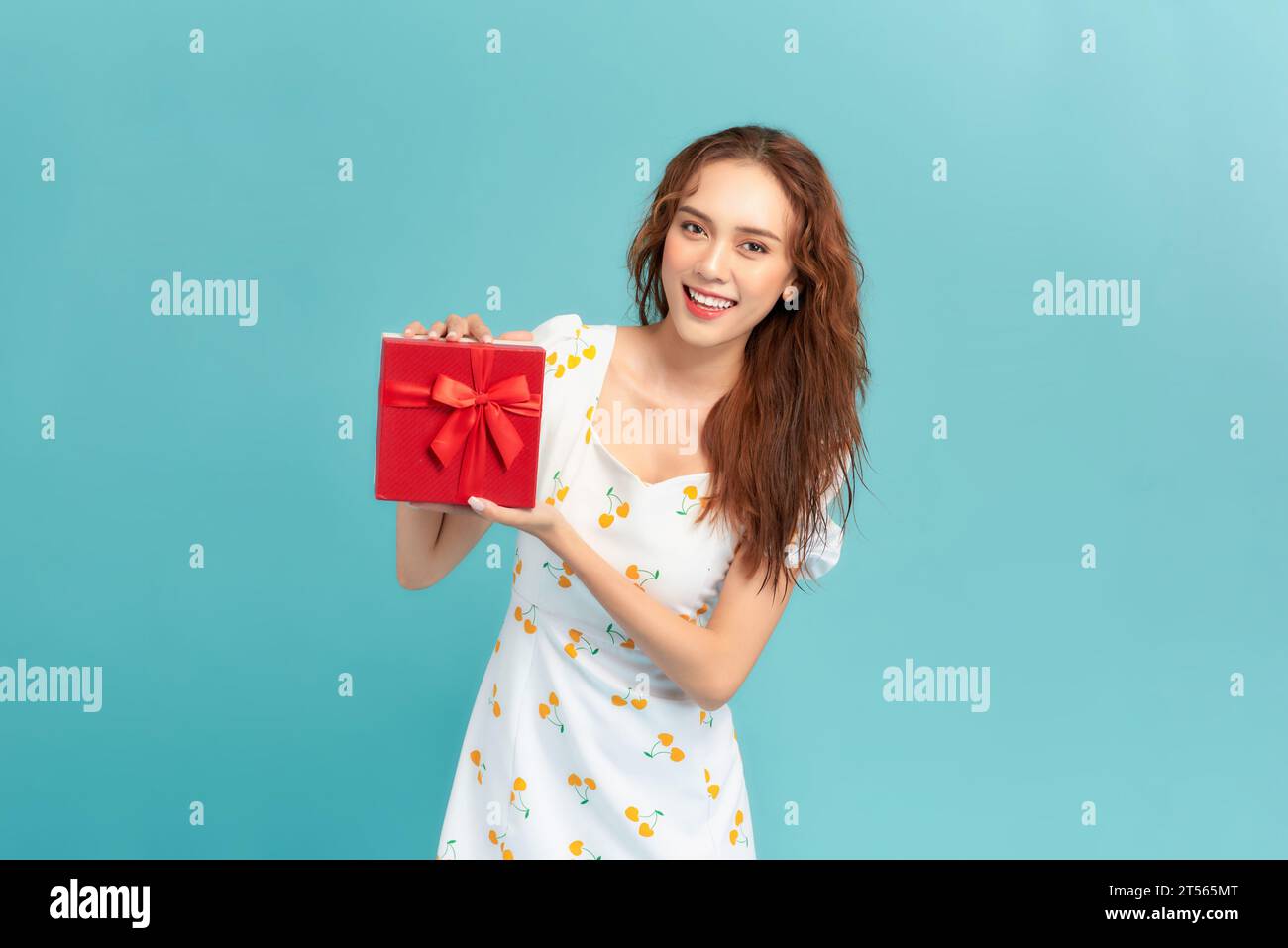 Portrait of happy charismatic girl shaking gift box wondering whats ...