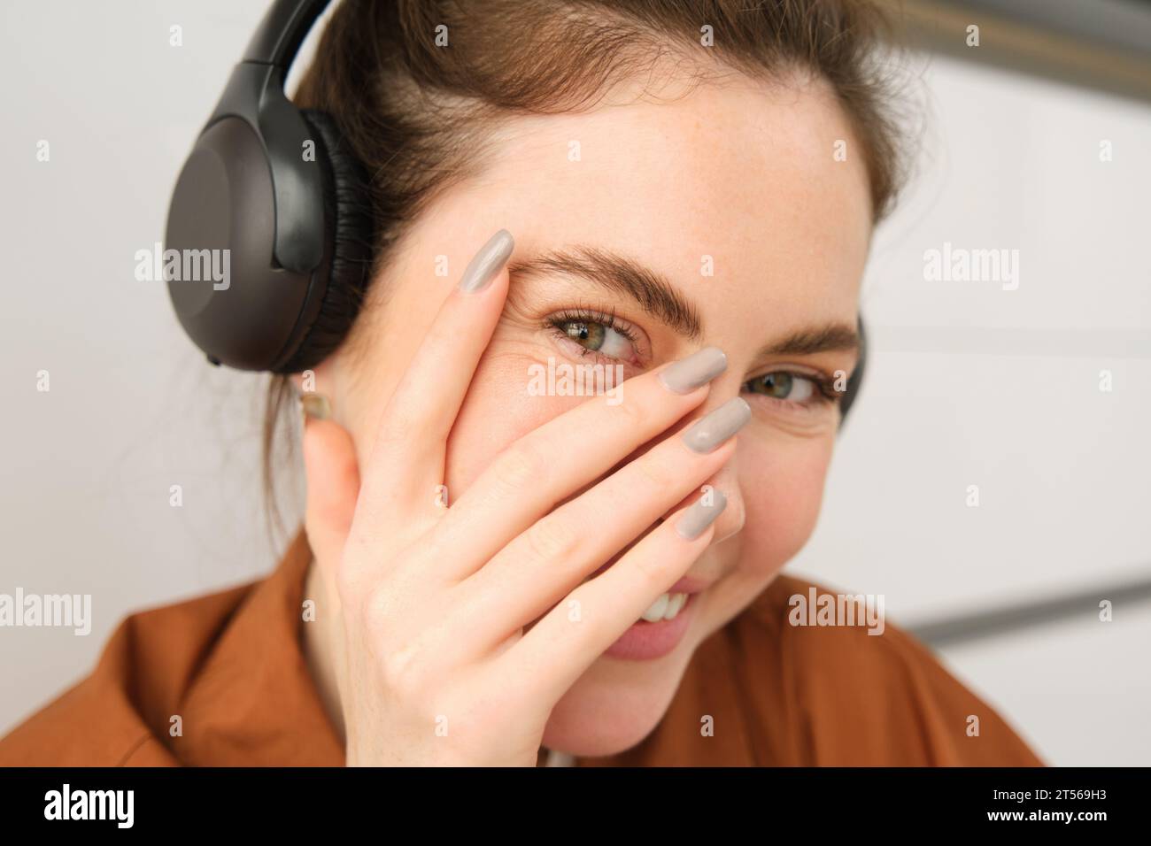 Cute smiling girl, blushes, hides face behind hand and laughing, wears ...
