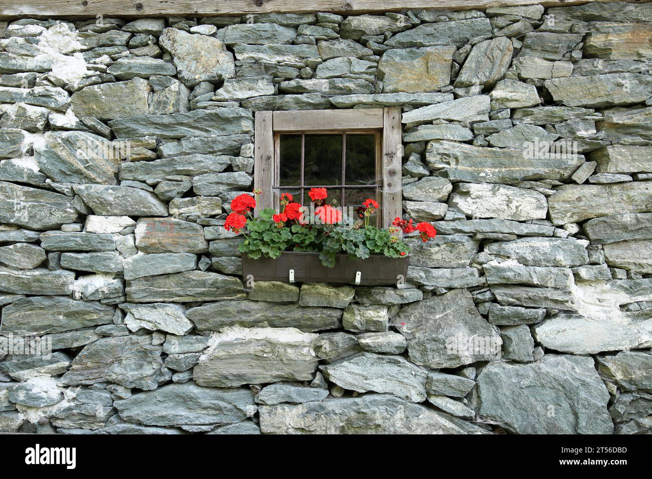 Stone alpine hut with wooden window with flowers in Pinzgau Stock Photo ...