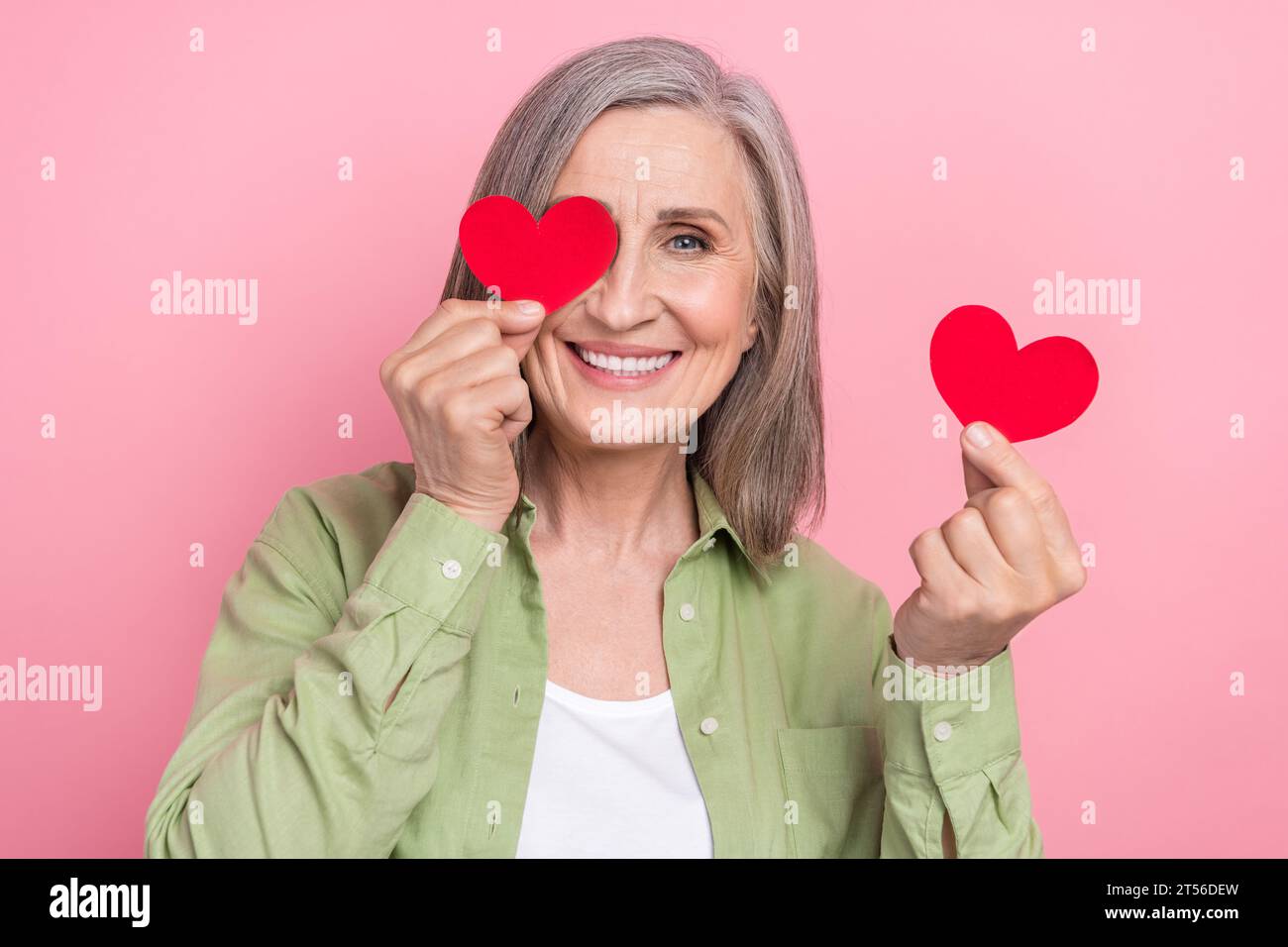 Portrait photo of cheerful old lady playful hiding her eye red paper ...