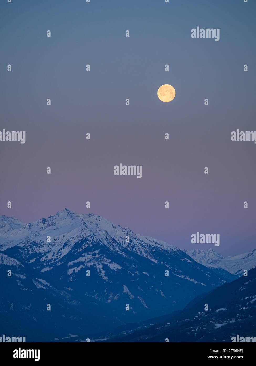 Snowy winter alpine landscape after sunset, pink purple sky with a full ...