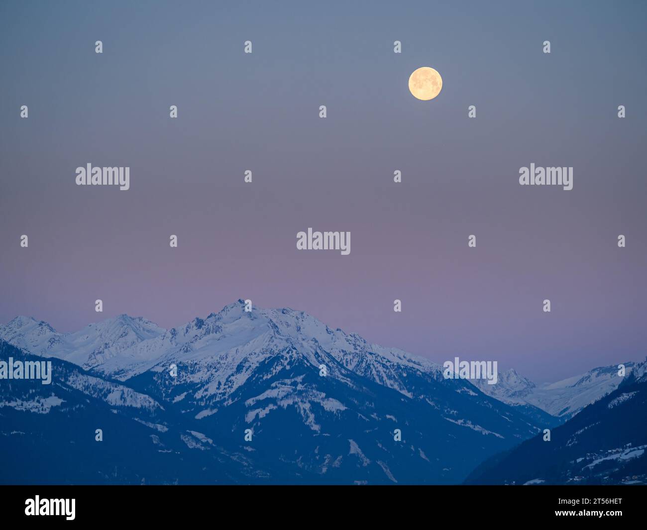 Snowy winter alpine landscape after sunset, pink purple sky with a full ...