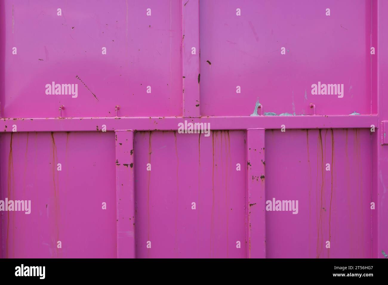 Pink painted metal container with rust stains, scratches and marks ...