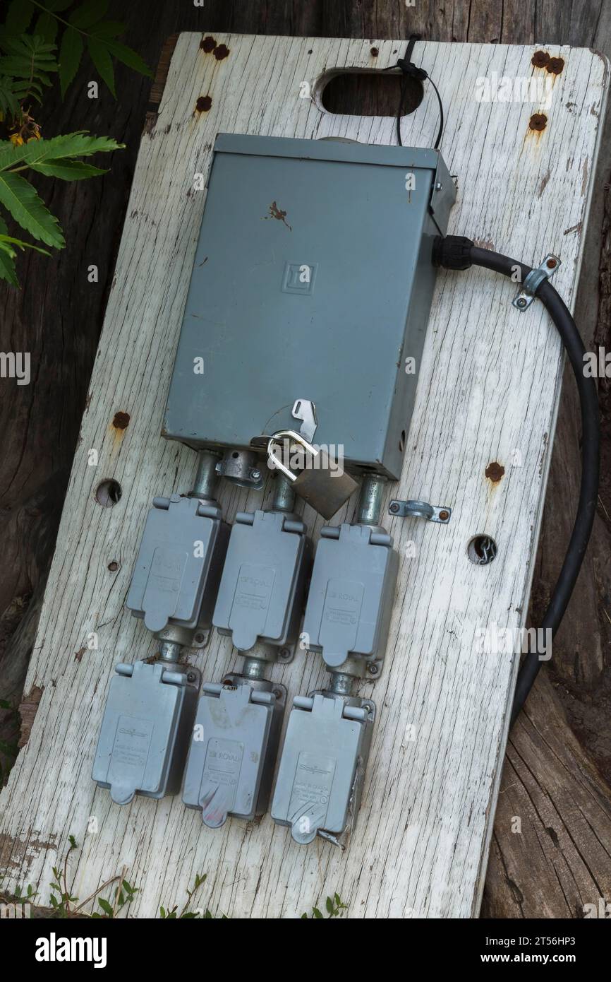 Locked grey metal electrical distribution box and outlets for plugging ...