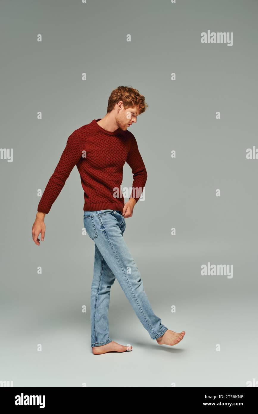 handsome appealing bearded man in warm sweater walking barefoot on gray ...