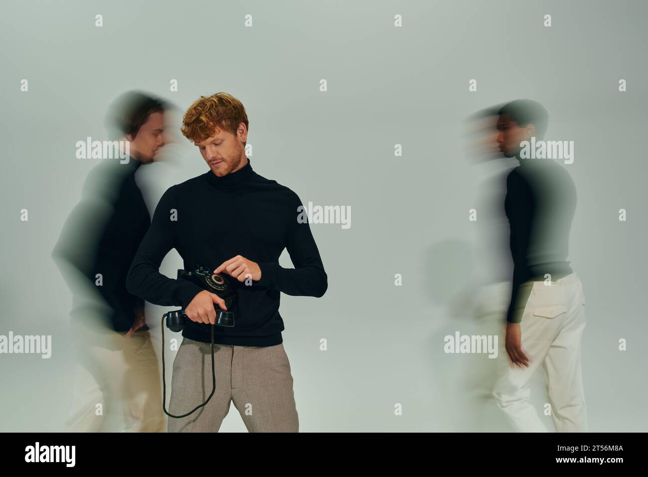red haired man with retro phone with motion blur of other male models ...