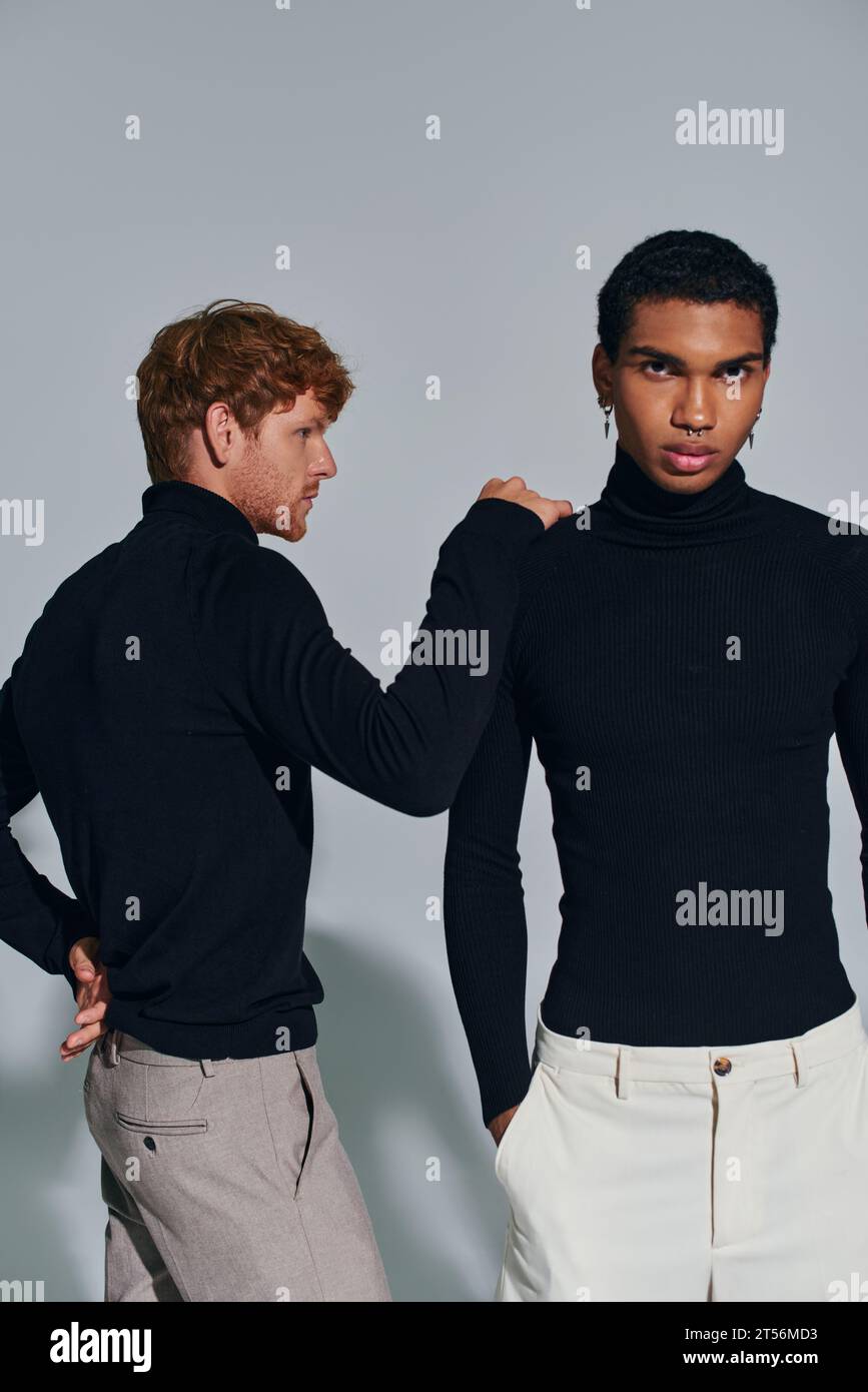 vertical shot of two appealing young men in elegant attires on gray ...