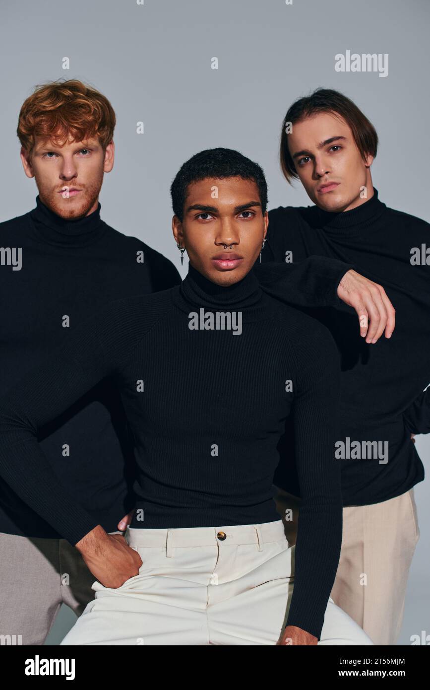 three interracial handsome men posing on gray backdrop wearing ...