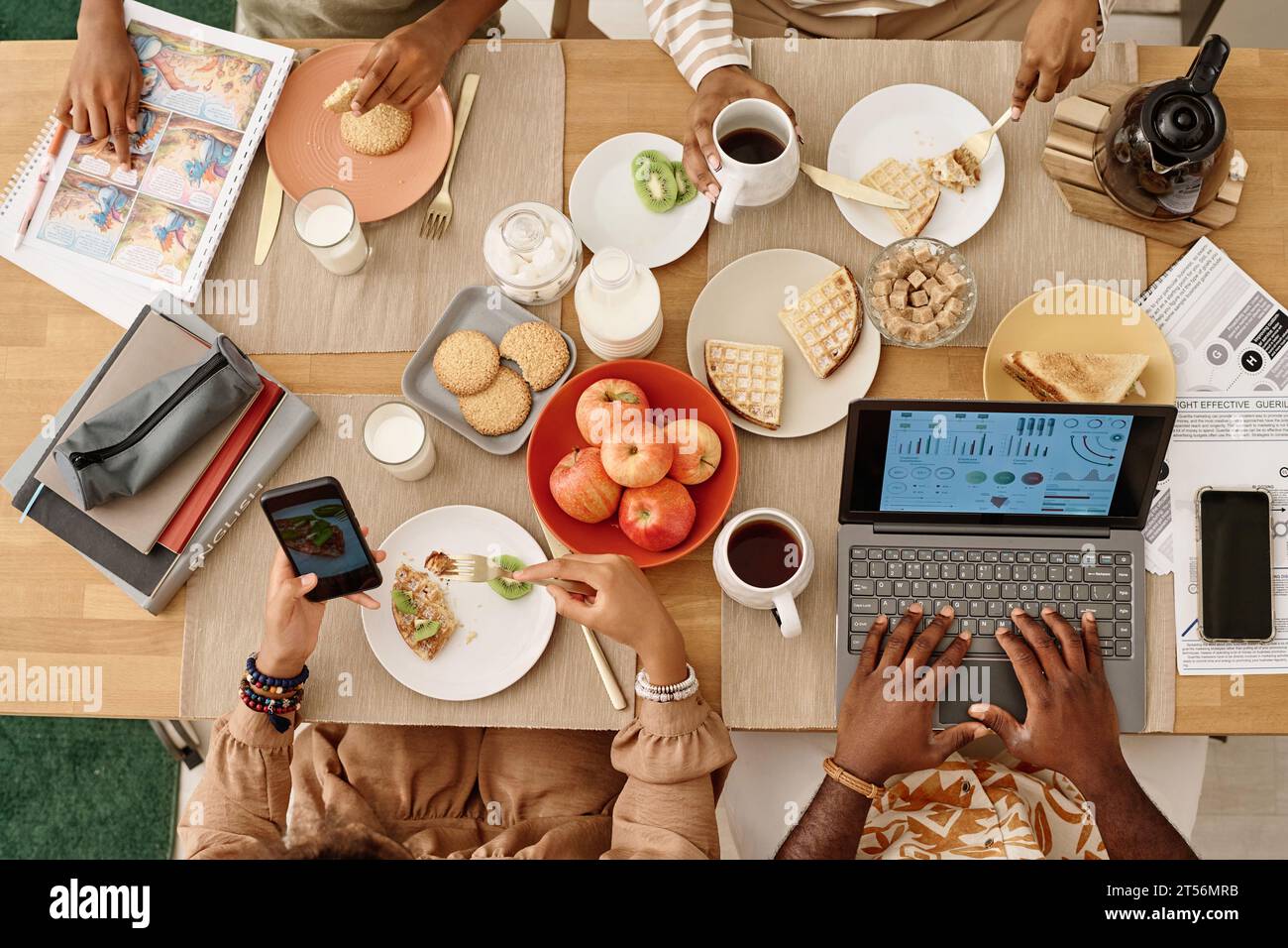 Family members busy with their own things when having breakfast at home ...