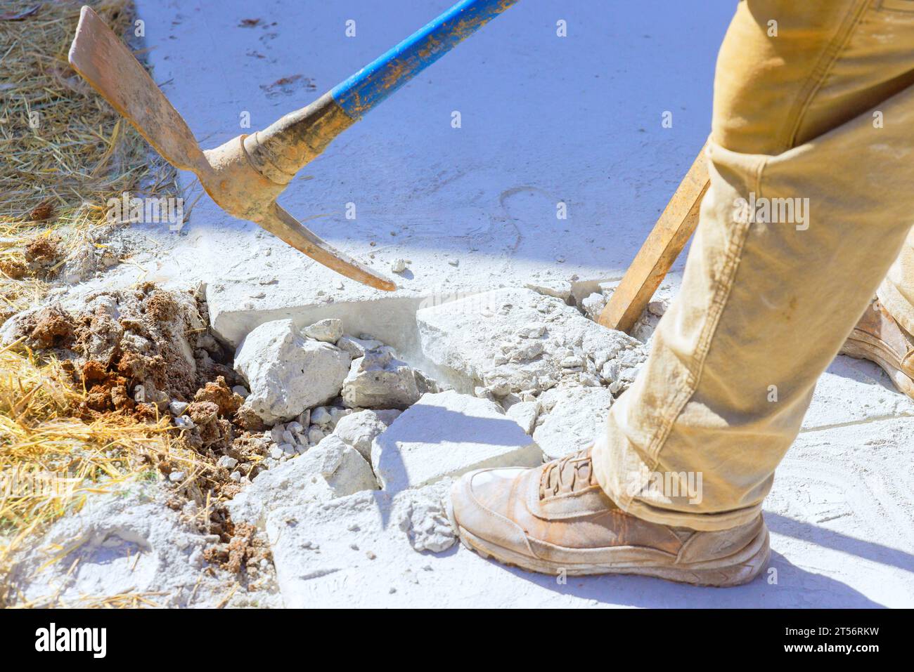 Construction site worker smashes old concrete driveway with pickaxe ...
