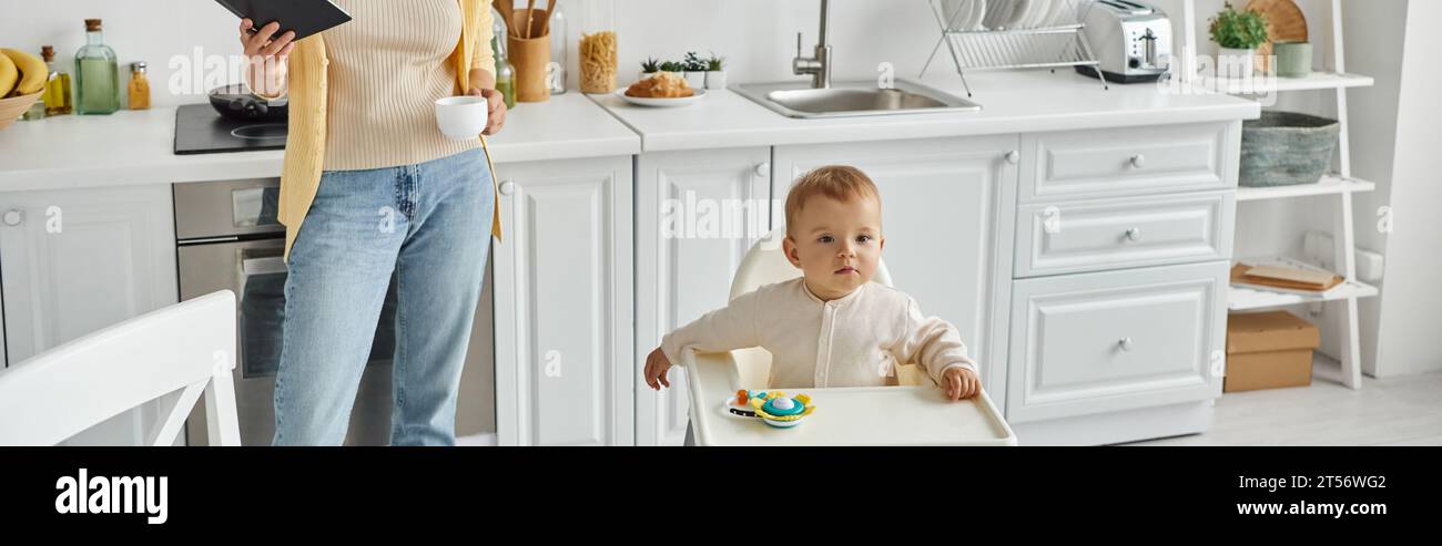 little girl sitting in baby chair near rattle toy near mom with ...