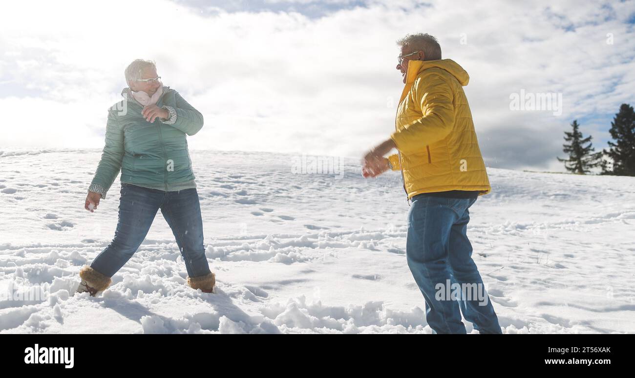 Happy senior couple having fun together during snowball fight outdoor ...