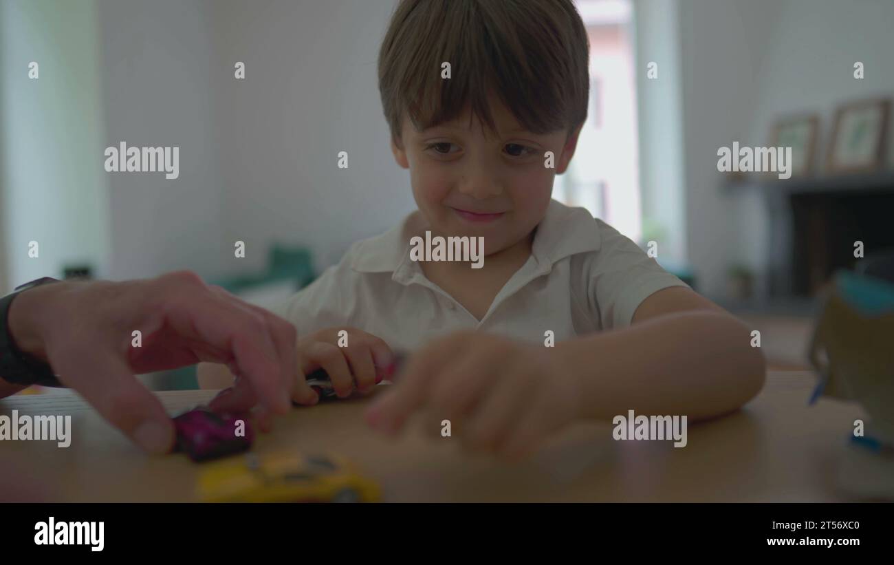 Little boy grabbing toy vehicles from table after unwrapping gift ...