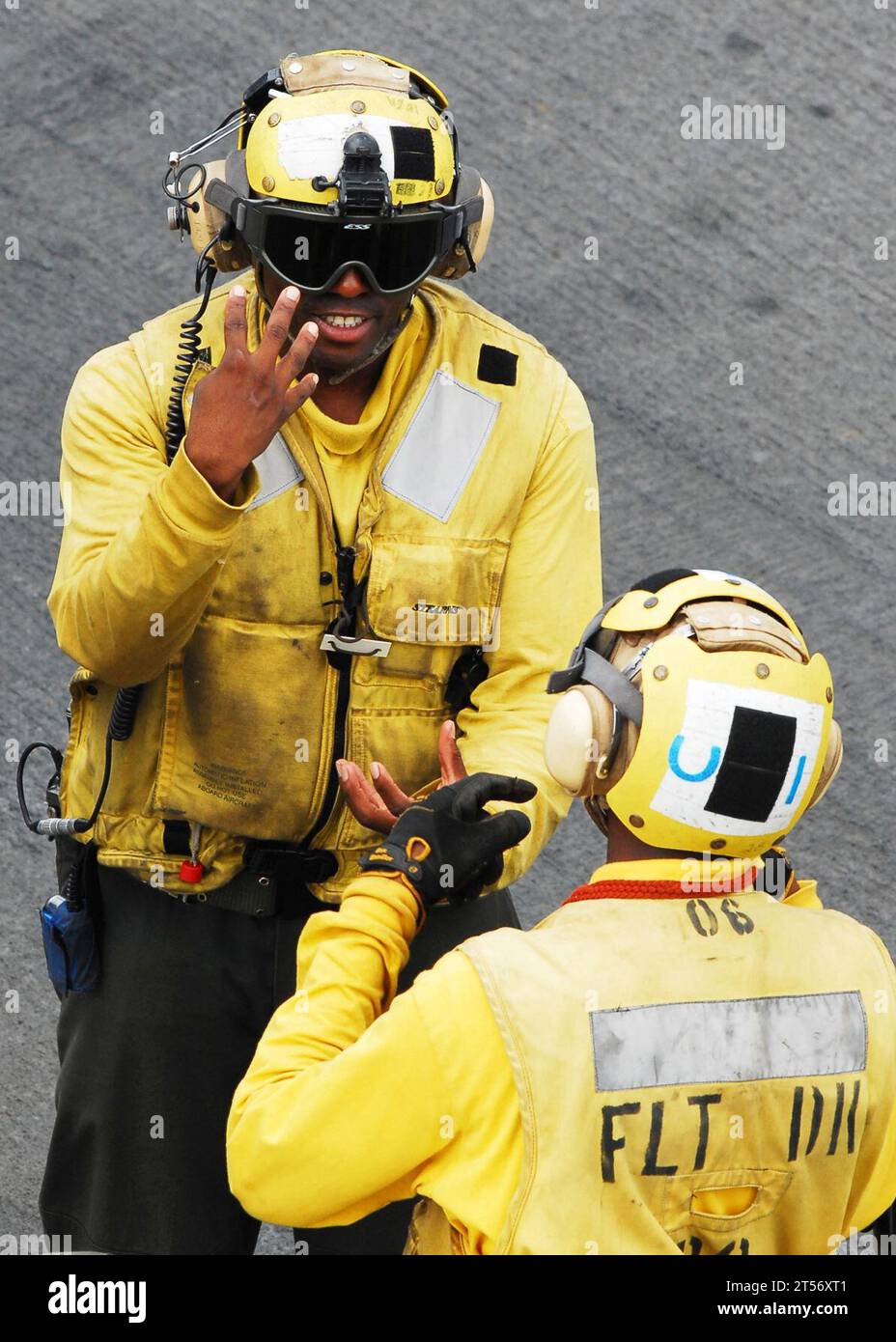 US Navy A flight deck crewman uses hand signals to communicate with ...