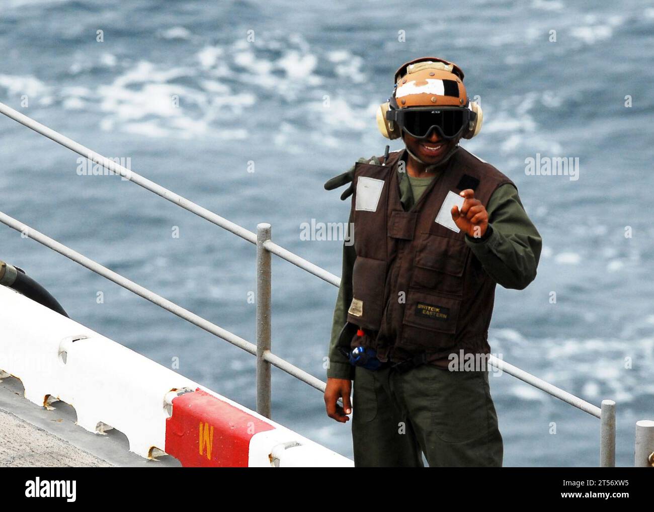 US Navy A flight deck crewman uses hand signals to communicate with ...