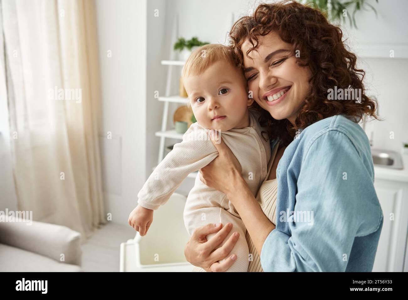 overjoyed woman with closed eyes holding and embracing adorable baby ...