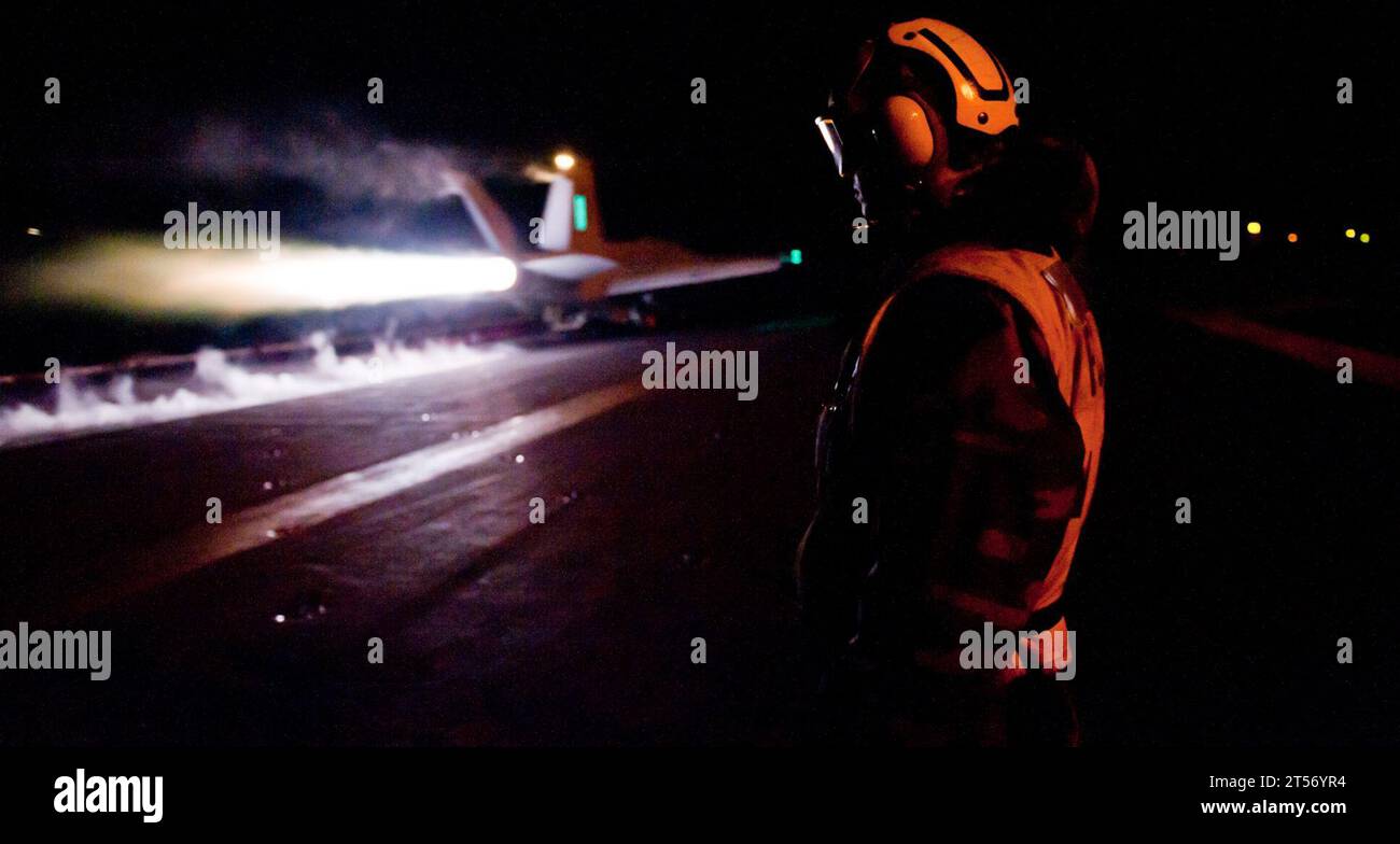 US Navy A Sailor observes as an aircraft launches during night flight ...