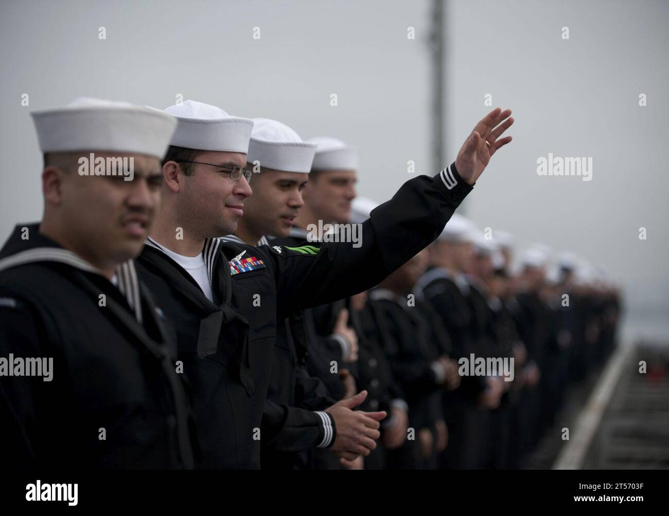 US Navy A Sailor waves goodbye to loved ones on the pier while manning ...