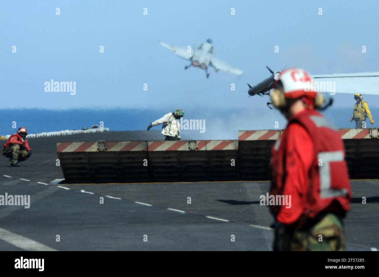 US Navy As the jet blast deflectors retracts, flight deck personnel get ...