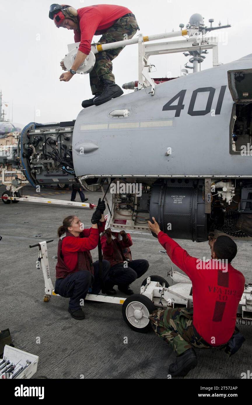 US Navy Aviation ordnancemen hoist an M61A1 machine gun into an F18C ...