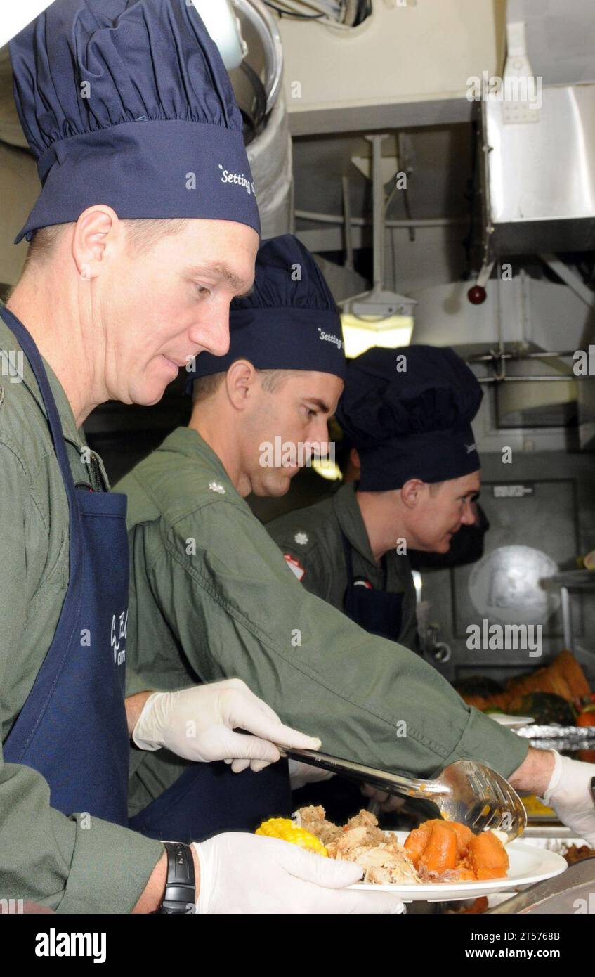 US Navy Officers serve Thanksgiving dinner in a galley aboard the ...