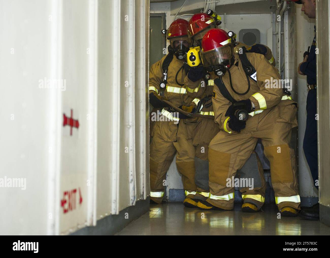 US Navy Sailors advance down a passageway during a general quarters ...