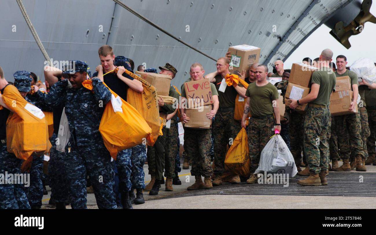 US Navy Sailors and Marines move mail onto the amphibious assault ship ...