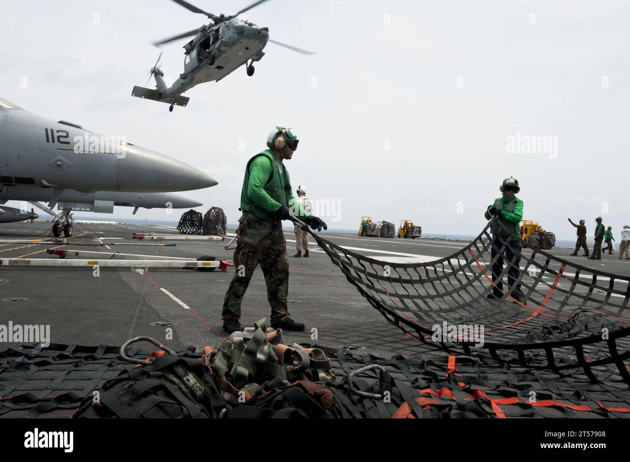 US Navy Sailors bundle cargo nets during a vertical replenishment ...