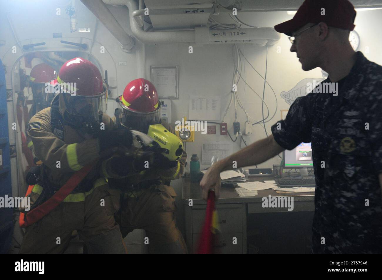 US Navy Sailors enter a smoke filled compartment during a damage ...