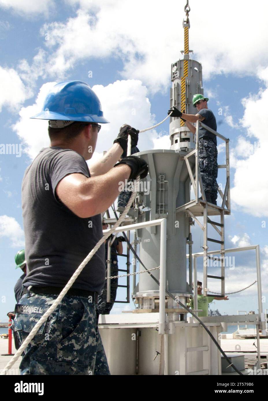 US Navy Sailors hold a tag line while offloading a lifting adapter from ...