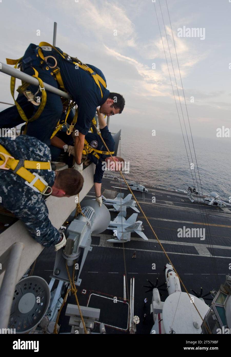 US Navy Sailors heave the ship's whistle up to the mast for ...