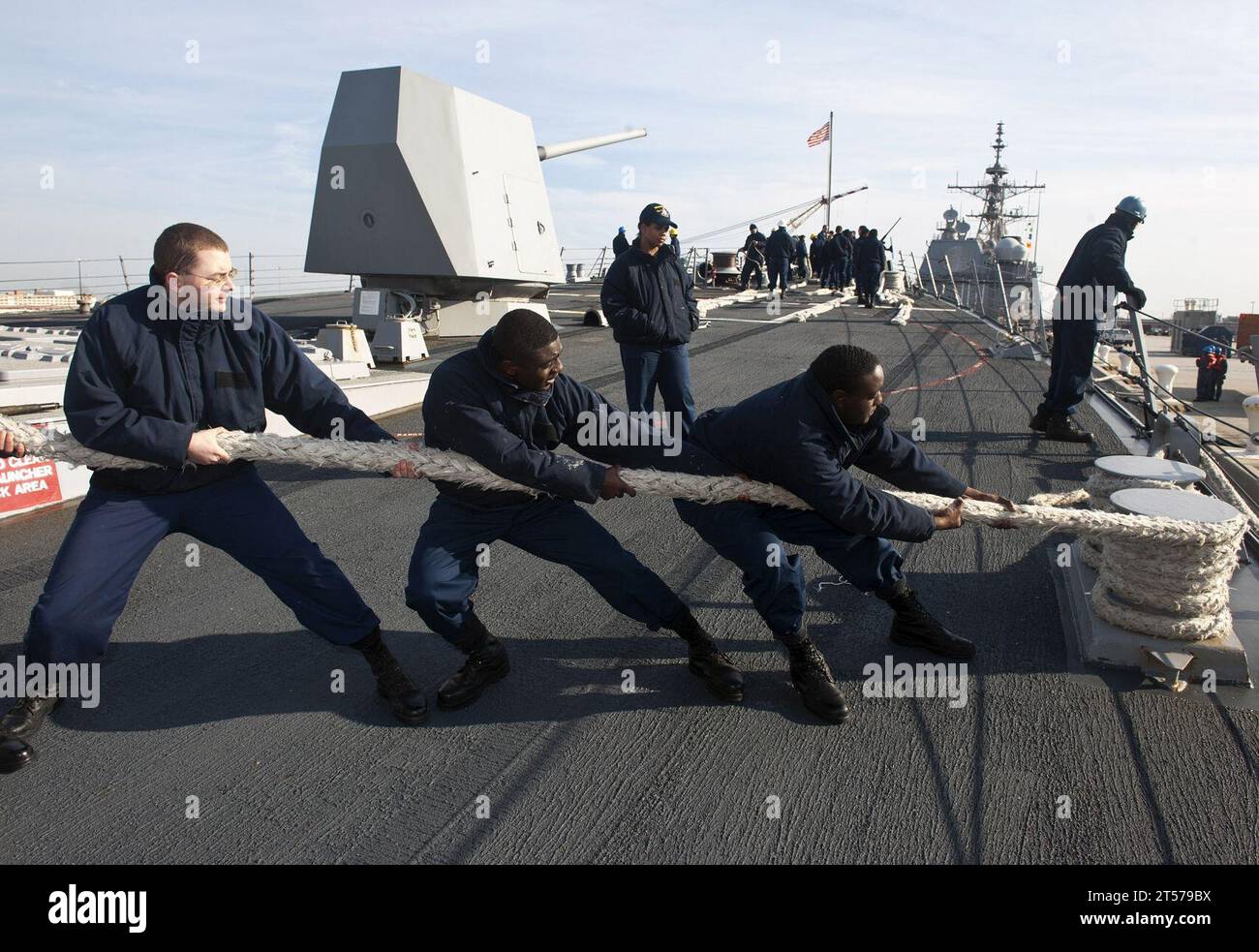 US Navy Sailors heave around a mooring line on the forecastle of ...