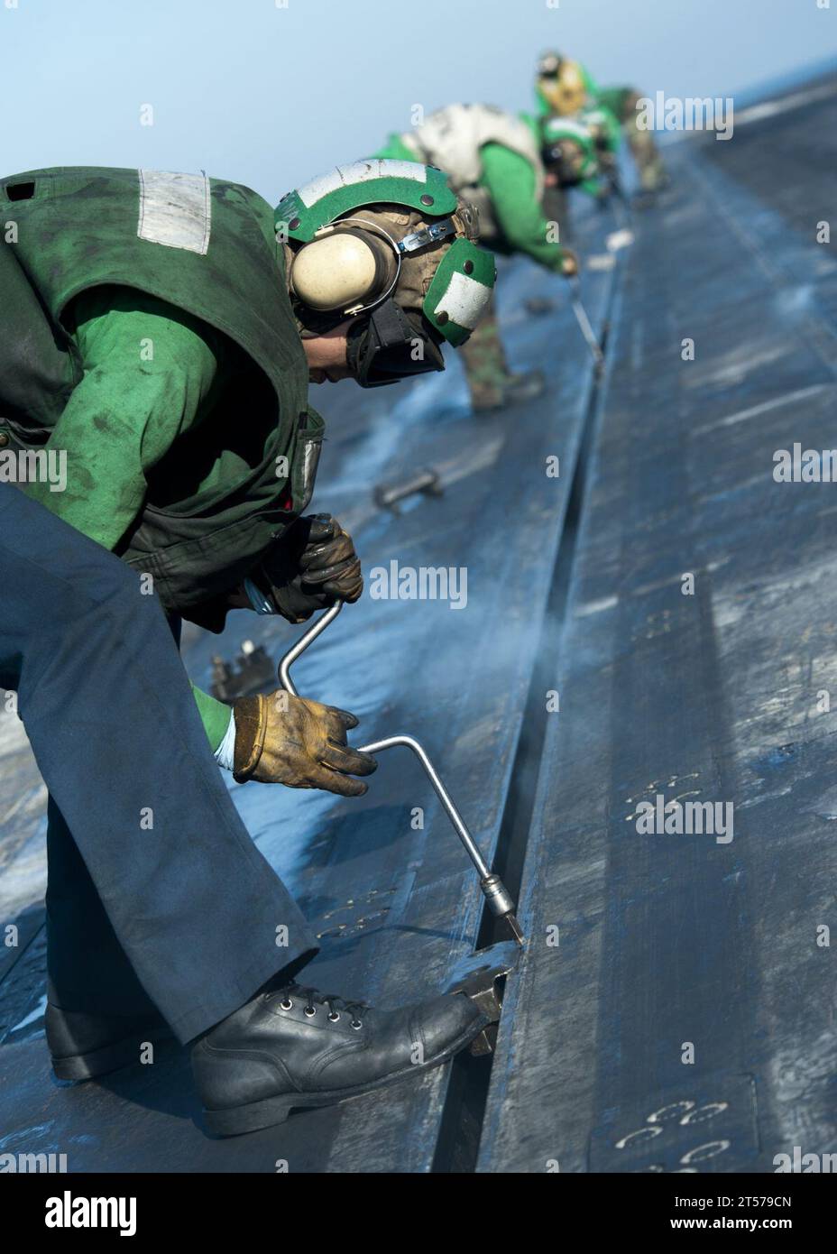 US Navy Sailors install buttons into the slot of a steam-powered ...