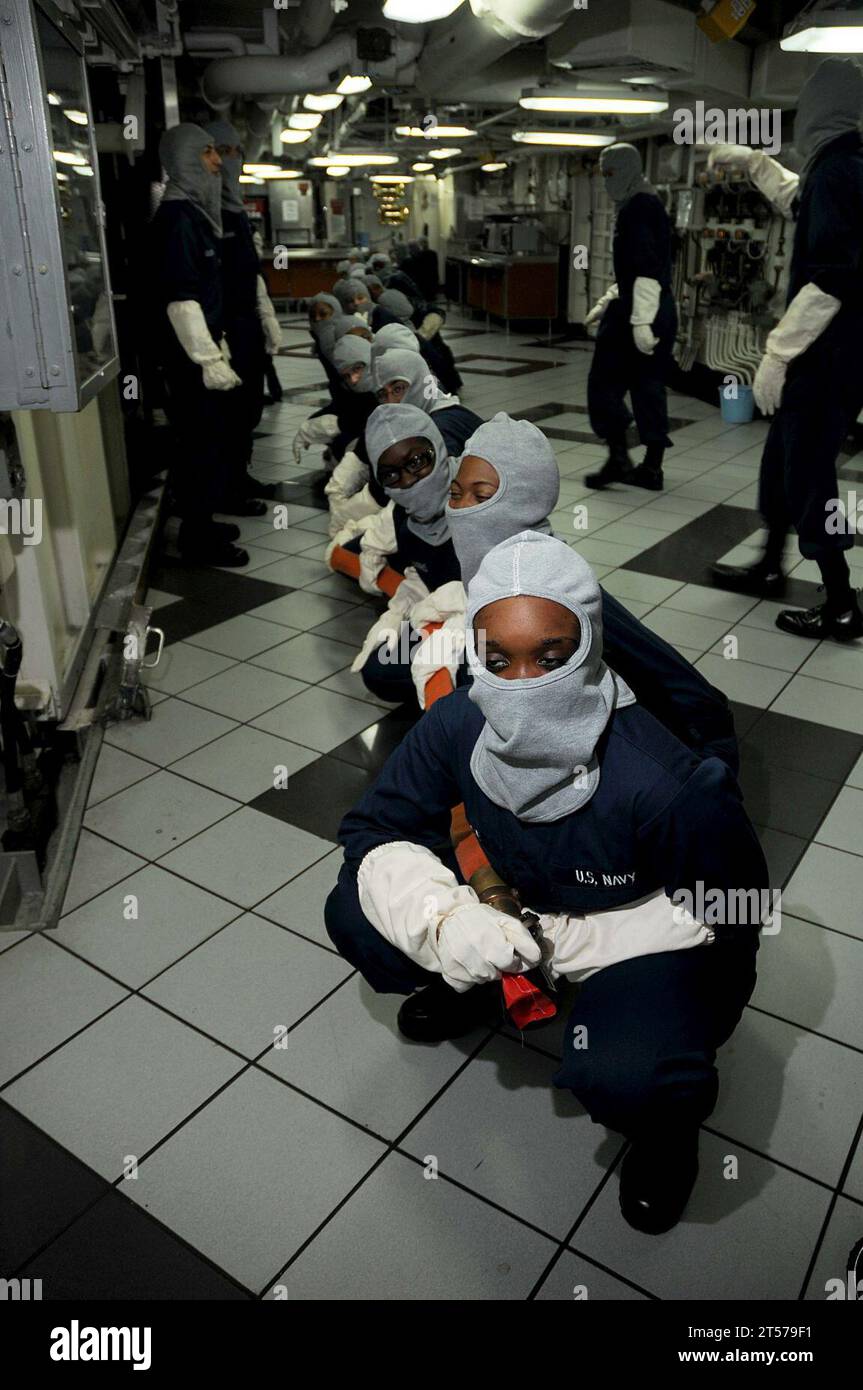 US Navy Sailors man a fire hose during a general quarters drill aboard ...