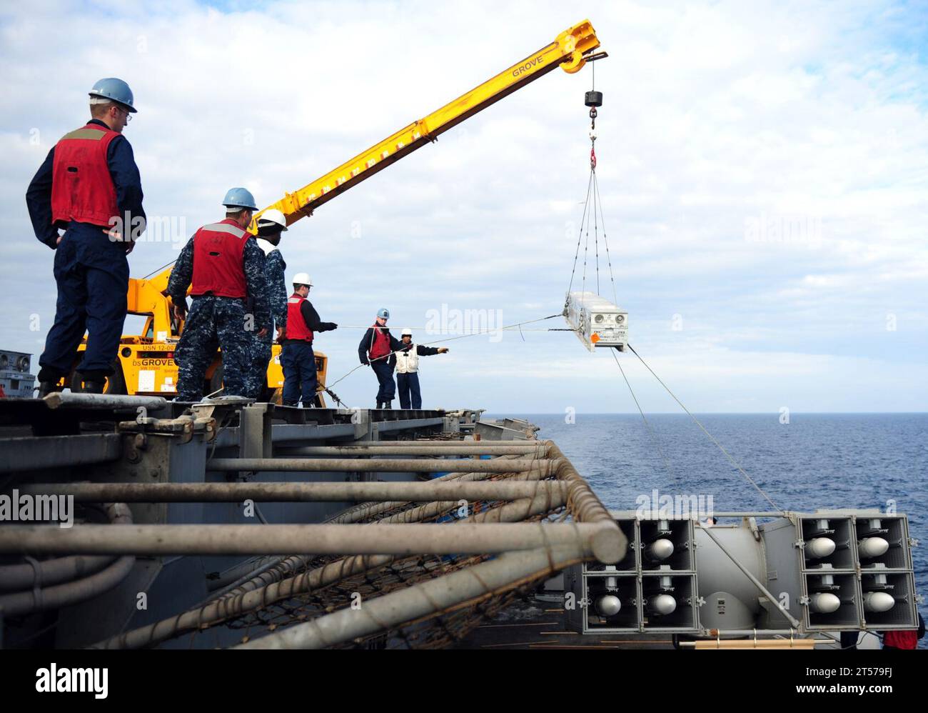 US Navy Sailors lower a weapon case from the flight deck of the ...