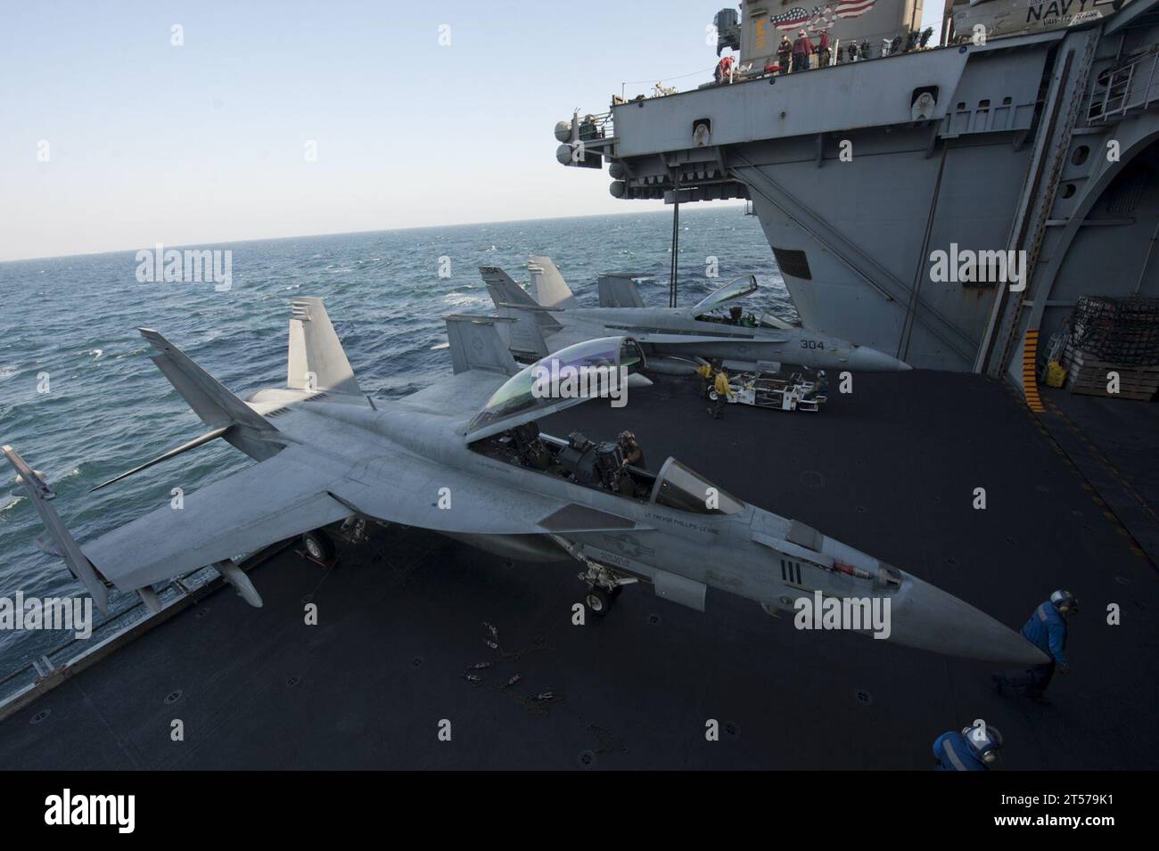 US Navy Sailors move aircraft onto an elevator aboard the Nimitz-class ...