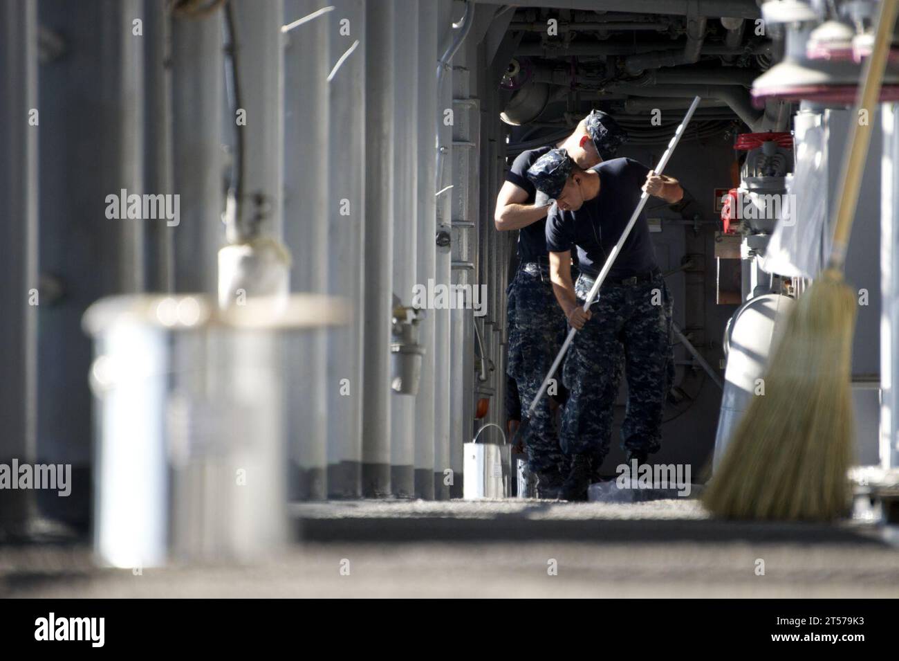 US Navy Sailors paint the deck on the starboard catwalk aboard the ...